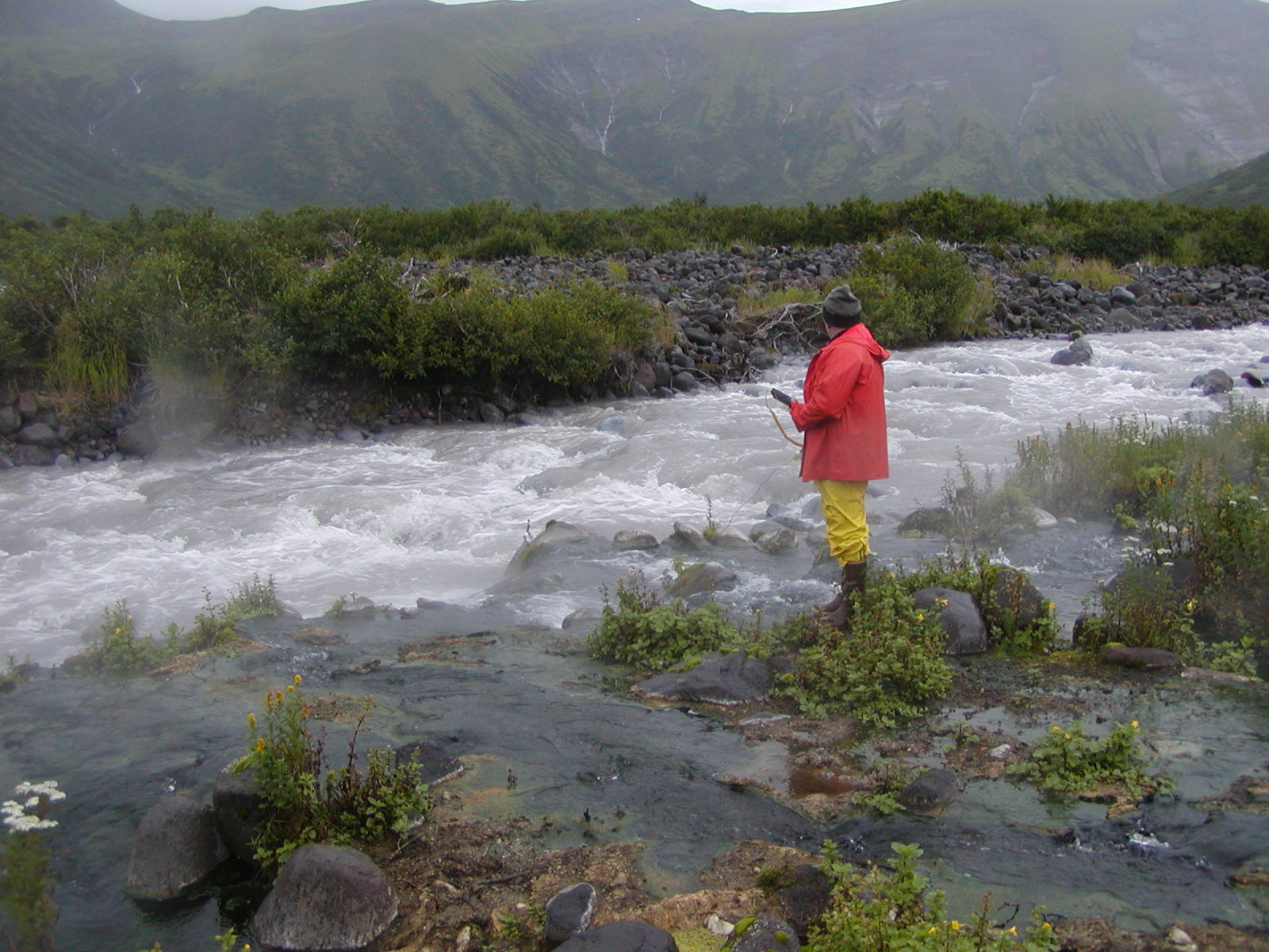 USGS/AVO geologist Game McGimsey takes a water temperature reading ...